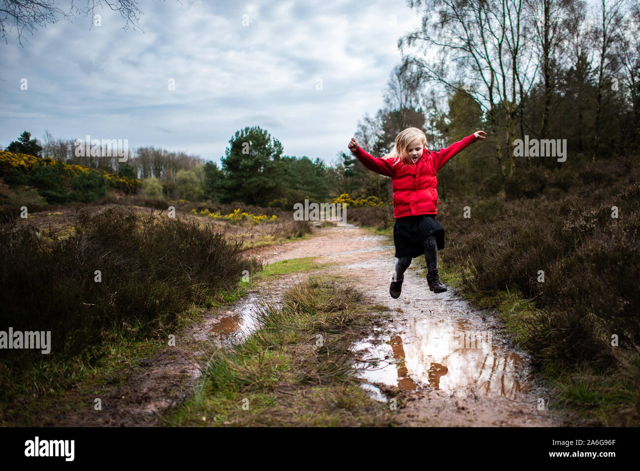 A little girl walks, runs and jumps through and into very muddy puddles ...
