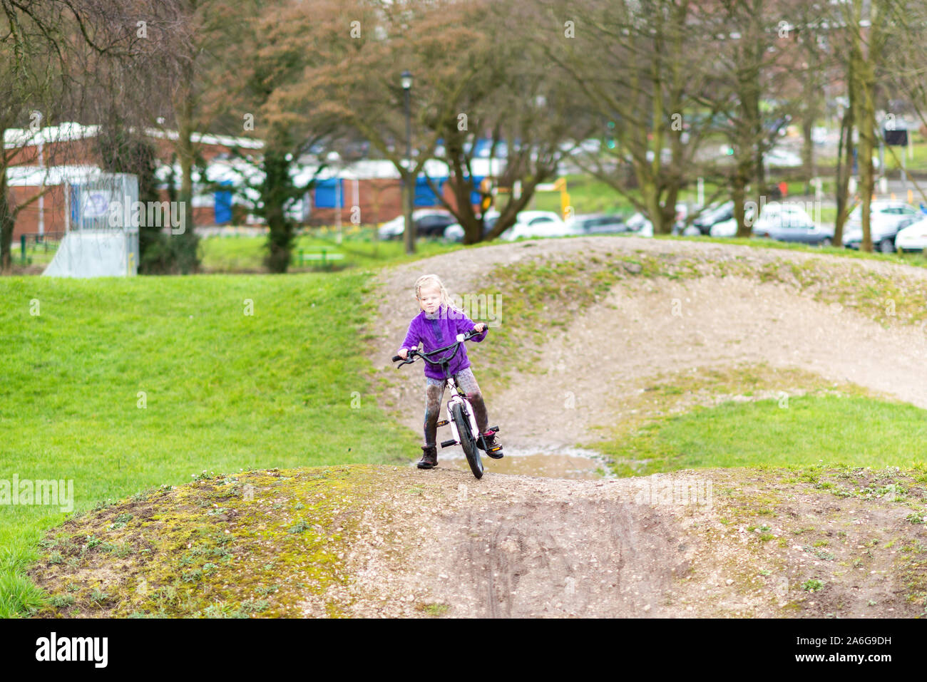 A pretty little girl with blonde hair and a purple jumper enjoys a day ...