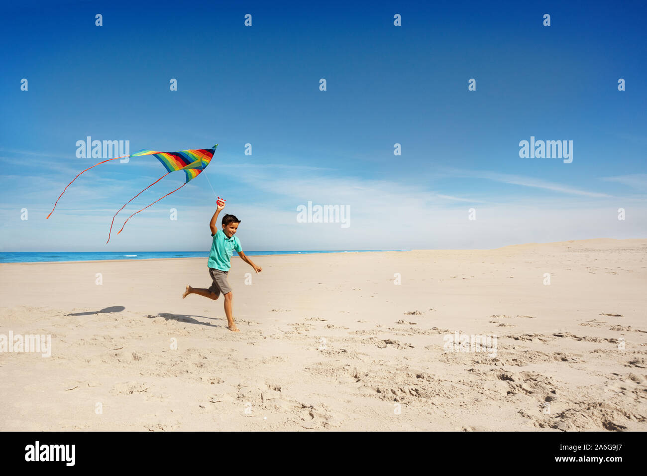 Little boy run alone with color kite on sea beach Stock Photo - Alamy