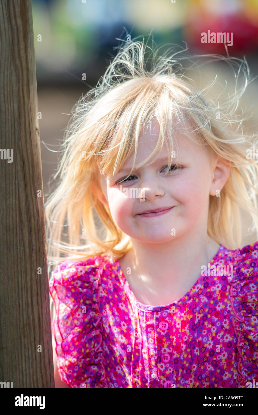 A cute, pretty little girl in a pretty pink dress skipping through a ...