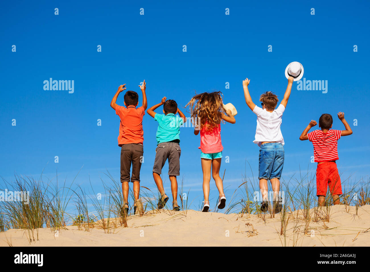 View from behind of a kids group jump on sand dune Stock Photo - Alamy