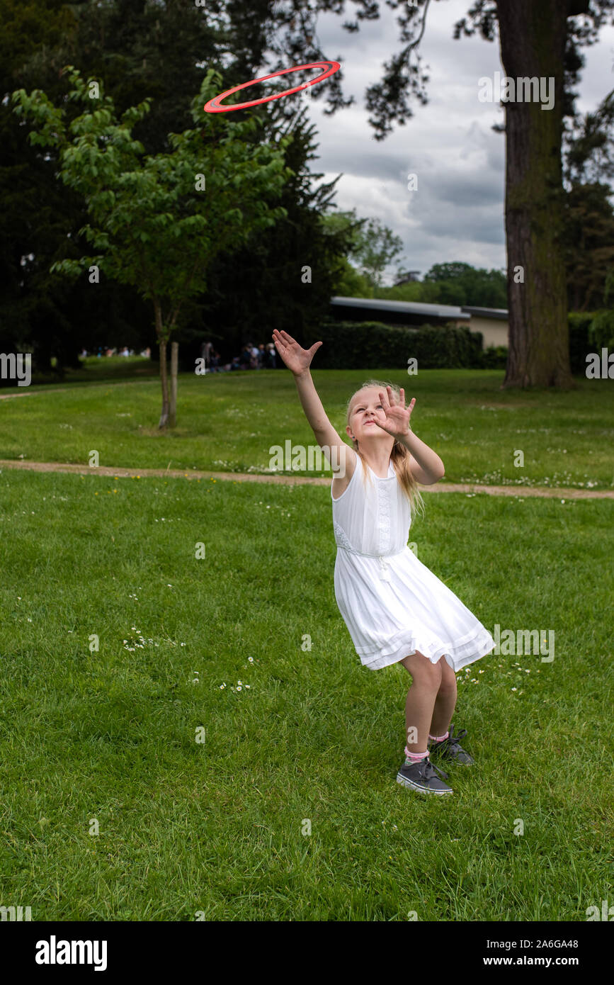 A pretty, cute little girl in a white dress playing frisbee, aerobee ...