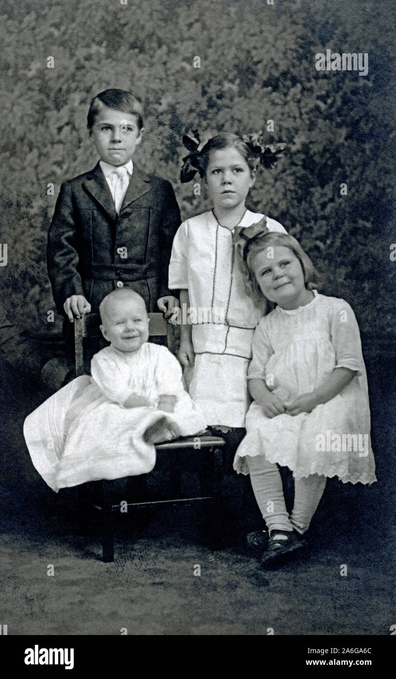A vintage family photograph of four childhood siblings of various ages ...
