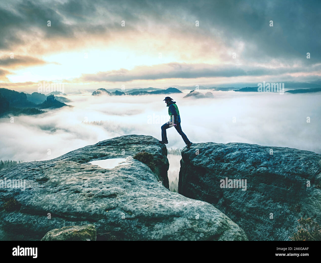 Hike in the autumn mountains. Man stay above heavy mist in deep valley ...