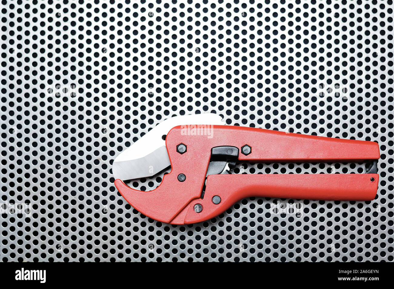 Red scissors for cutting plastic pipe on metal surface Stock Photo - Alamy