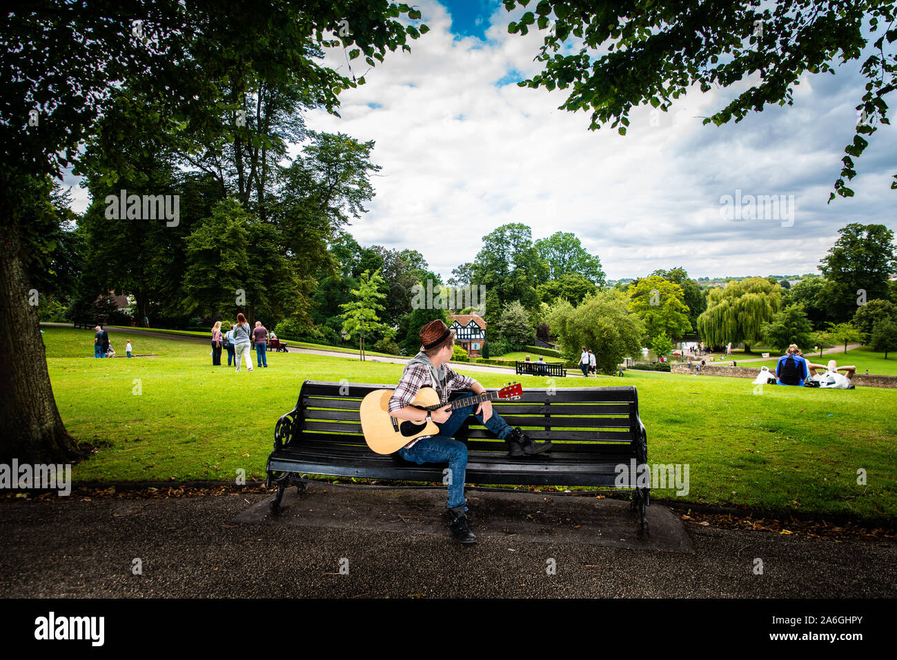 A handsome young man in a hat playing guitar and busking for money ...
