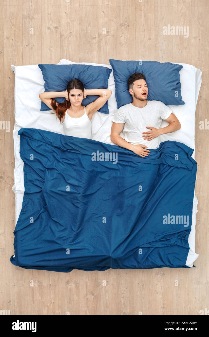 Bedtime. Young man sleeping yawning while woman covering ears angry ...