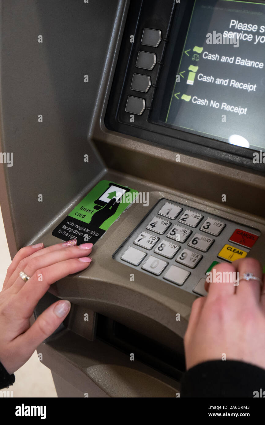 A young women using a cash machine, ATM to withdraw some money at the ...