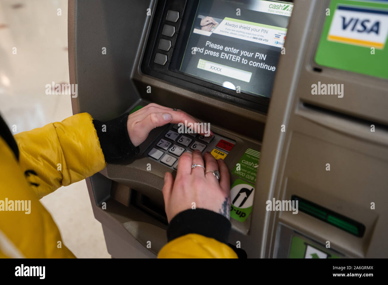 A young women using a cash machine, ATM to withdraw some money at the ...