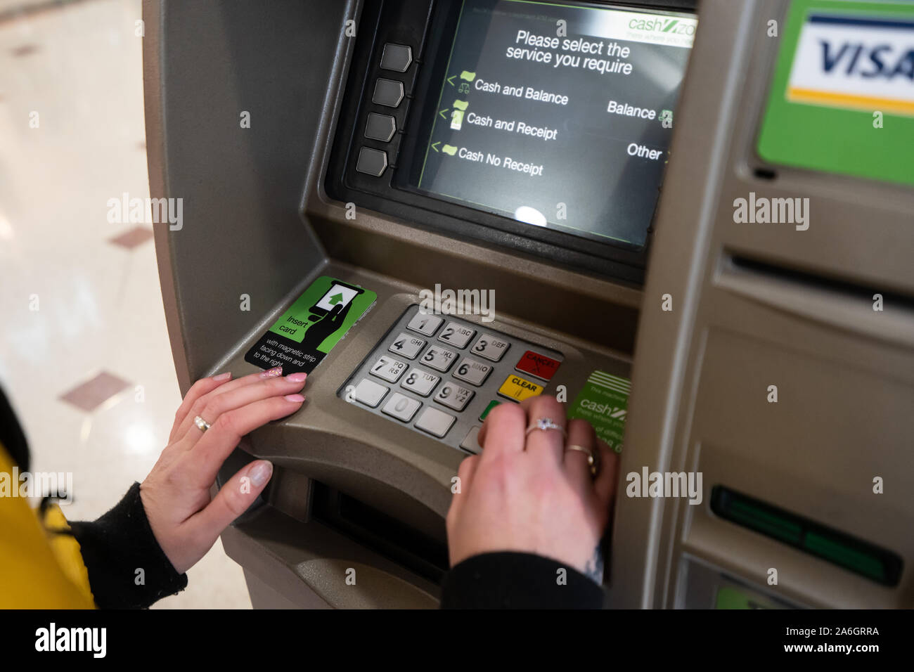 A young women using a cash machine, ATM to withdraw some money at the ...