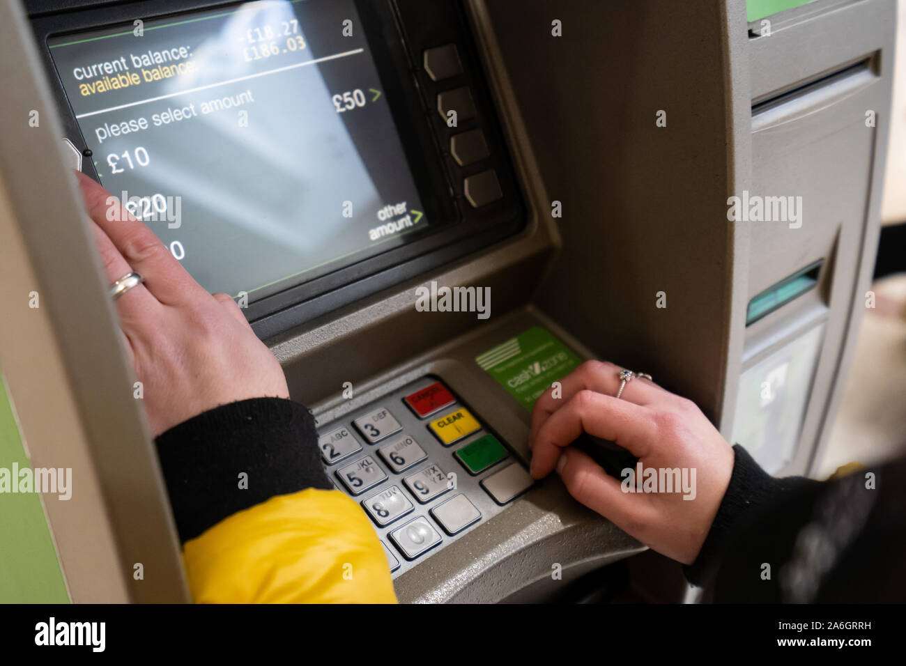 A young women using a cash machine, ATM to withdraw some money at the ...