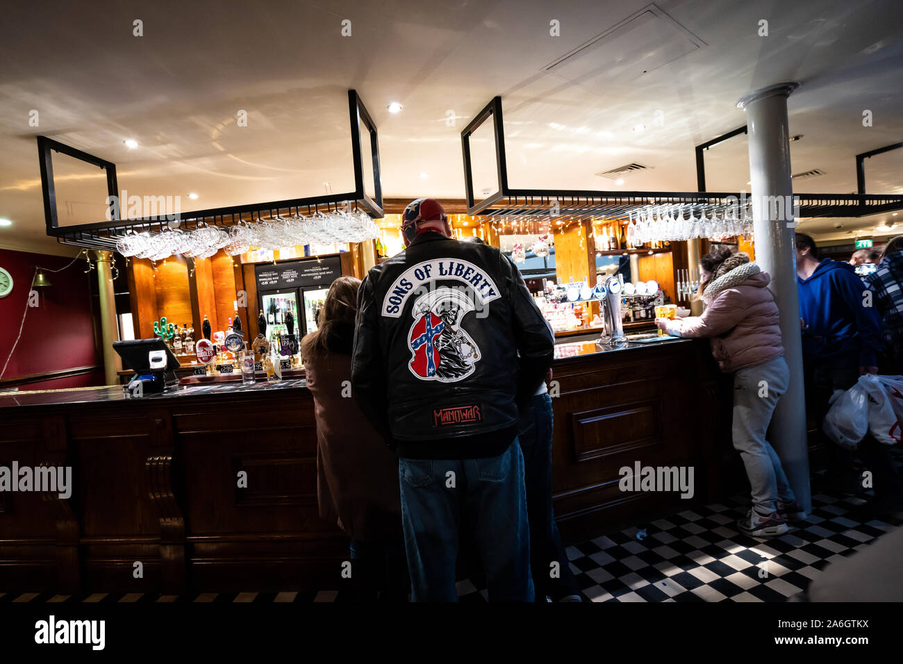A man wearing a bikers jacket, gang related clothing queuing at the bar ...