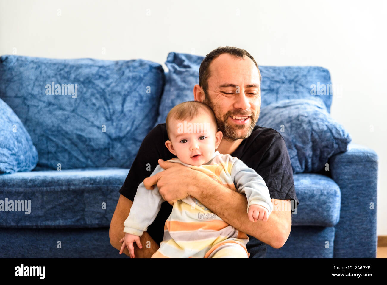 Father sitting on the floor with his baby in his arms in the living ...