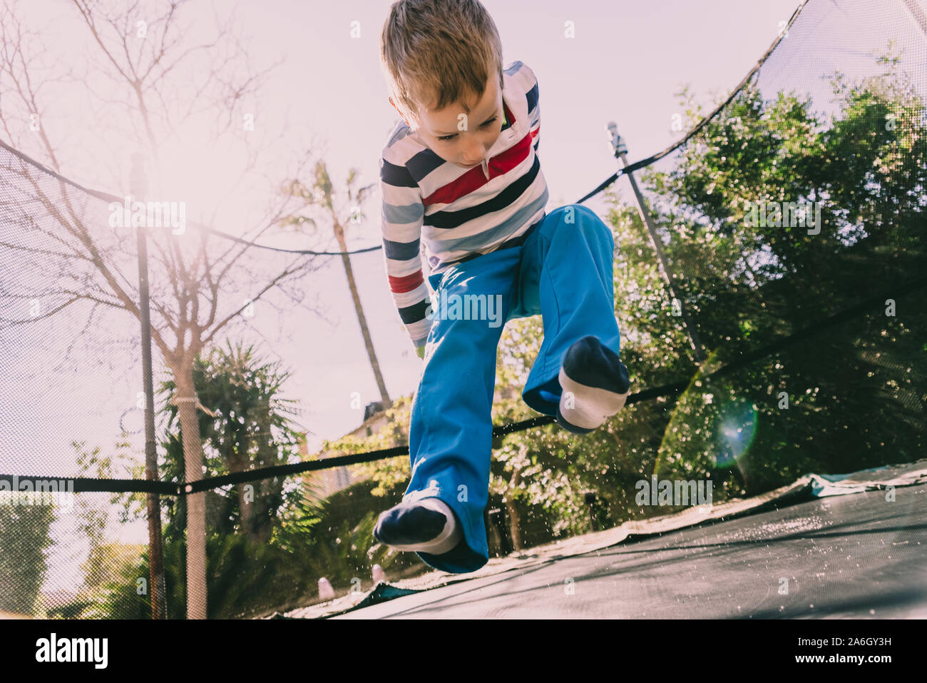 5 year old boy jumping on a trampoline enjoying his energy, face with ...