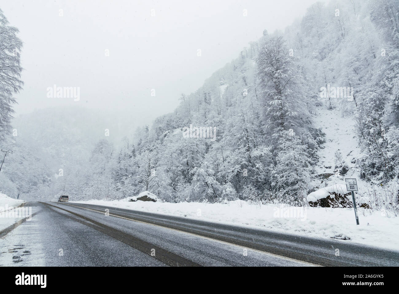 Snowy road scene in winter, with snowy trees, rocks and asphalt road ...
