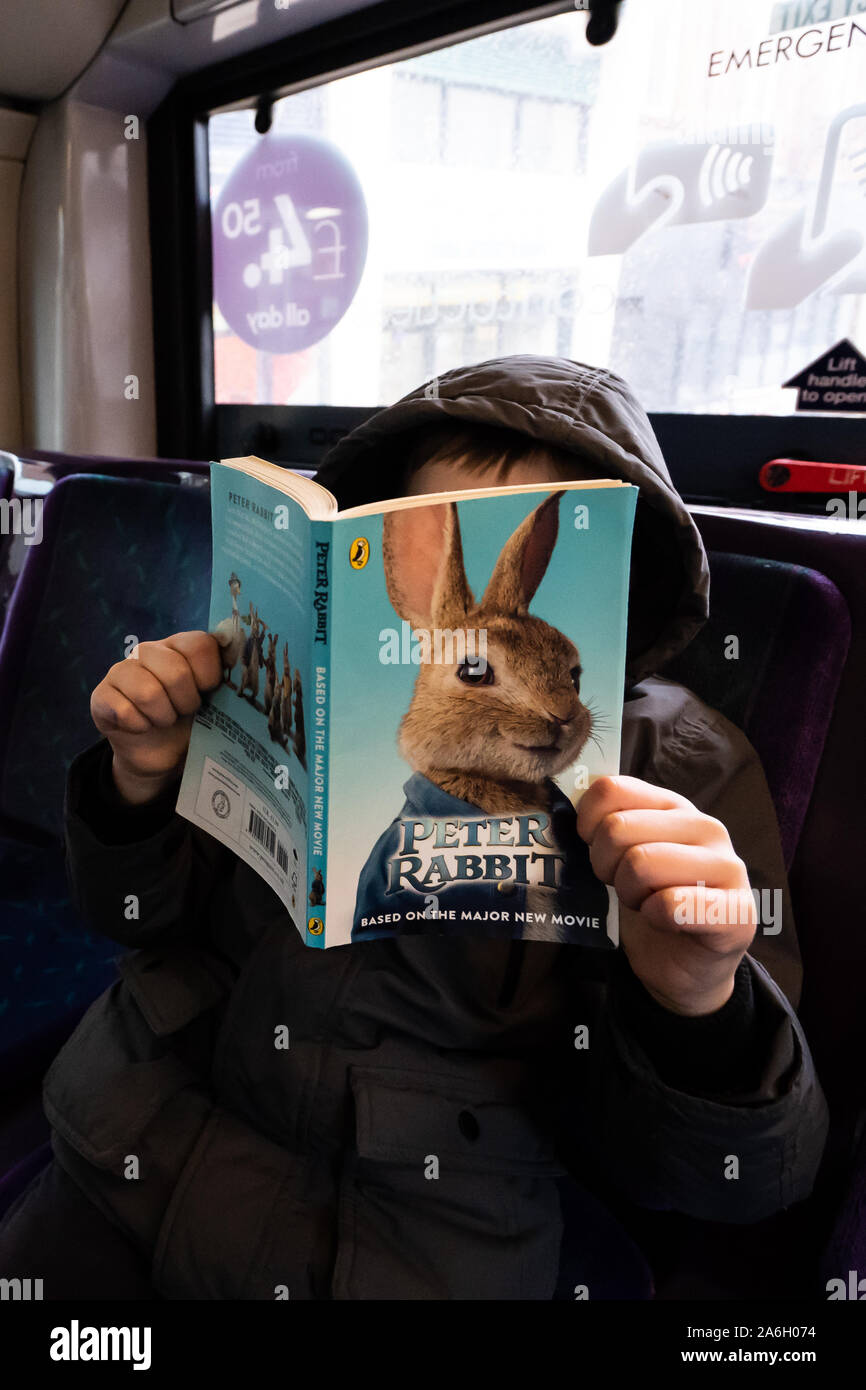 A little boy poses while reading a Peter Rabbit book on a bus from ...