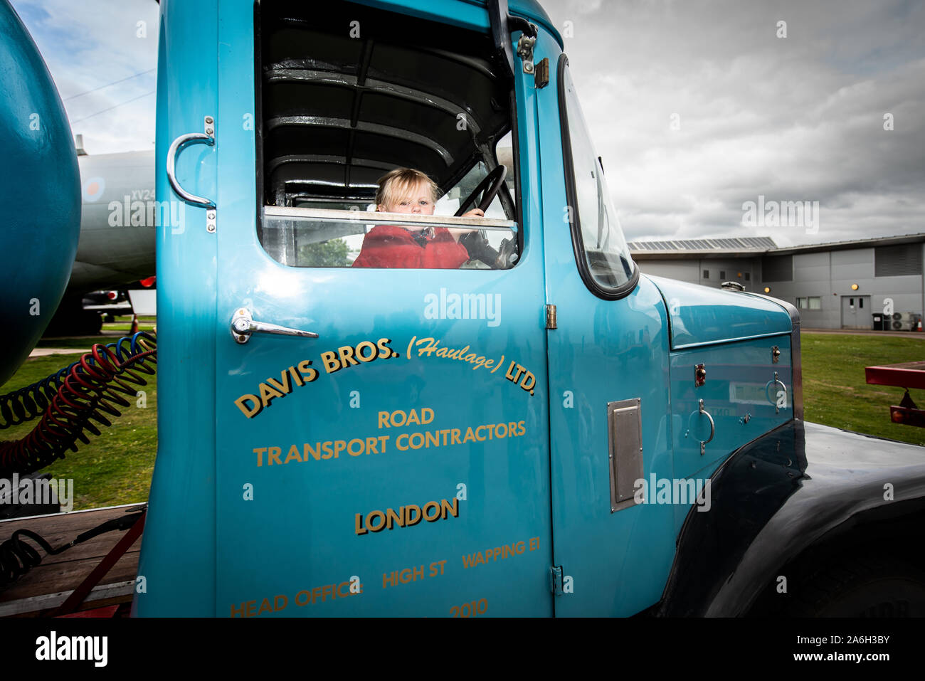 A cute, pretty little girl sits at the wheel of an old Davis Bros ...