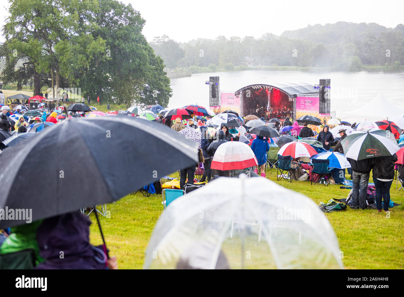 People cover under umbrella's at an outdoor music festival, raining ...