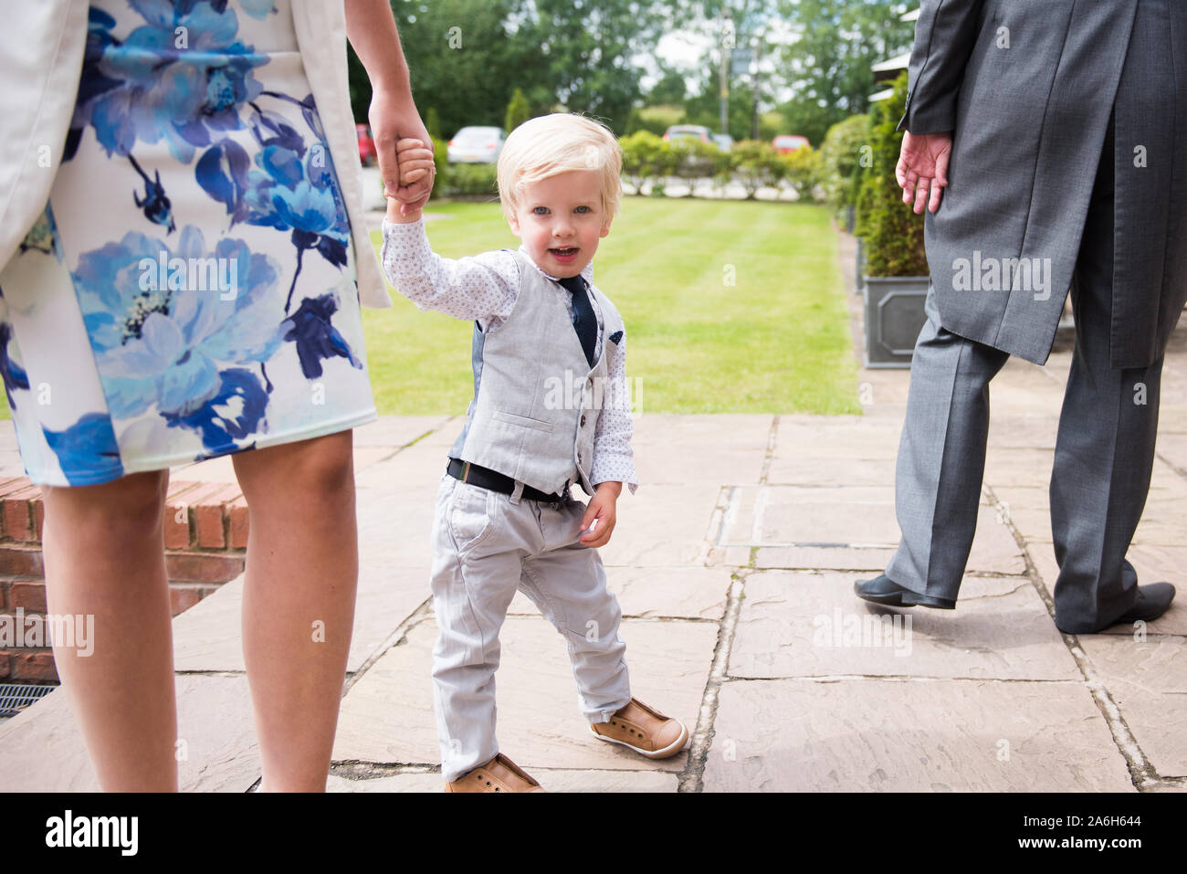 An adorable page boy posing for pictures on the big wedding day, family ...