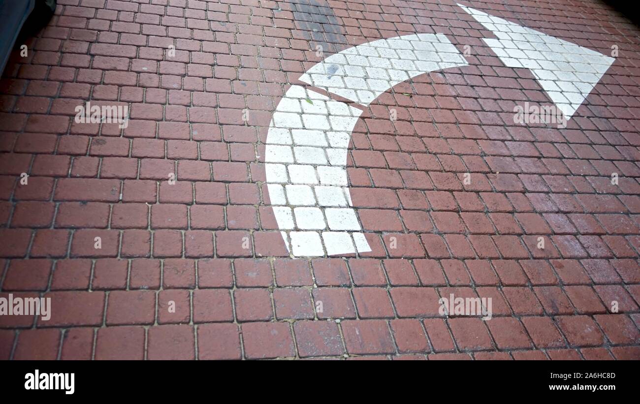 detail red brick cobblestone street with a white painted arrow curving ...