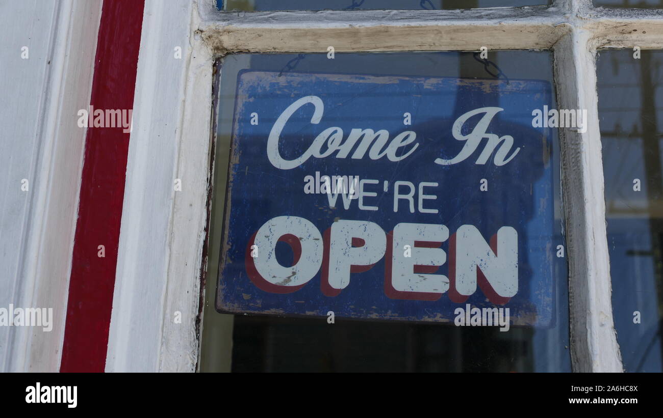 Come In We're Open sign hanging in the window of white painted shabby ...