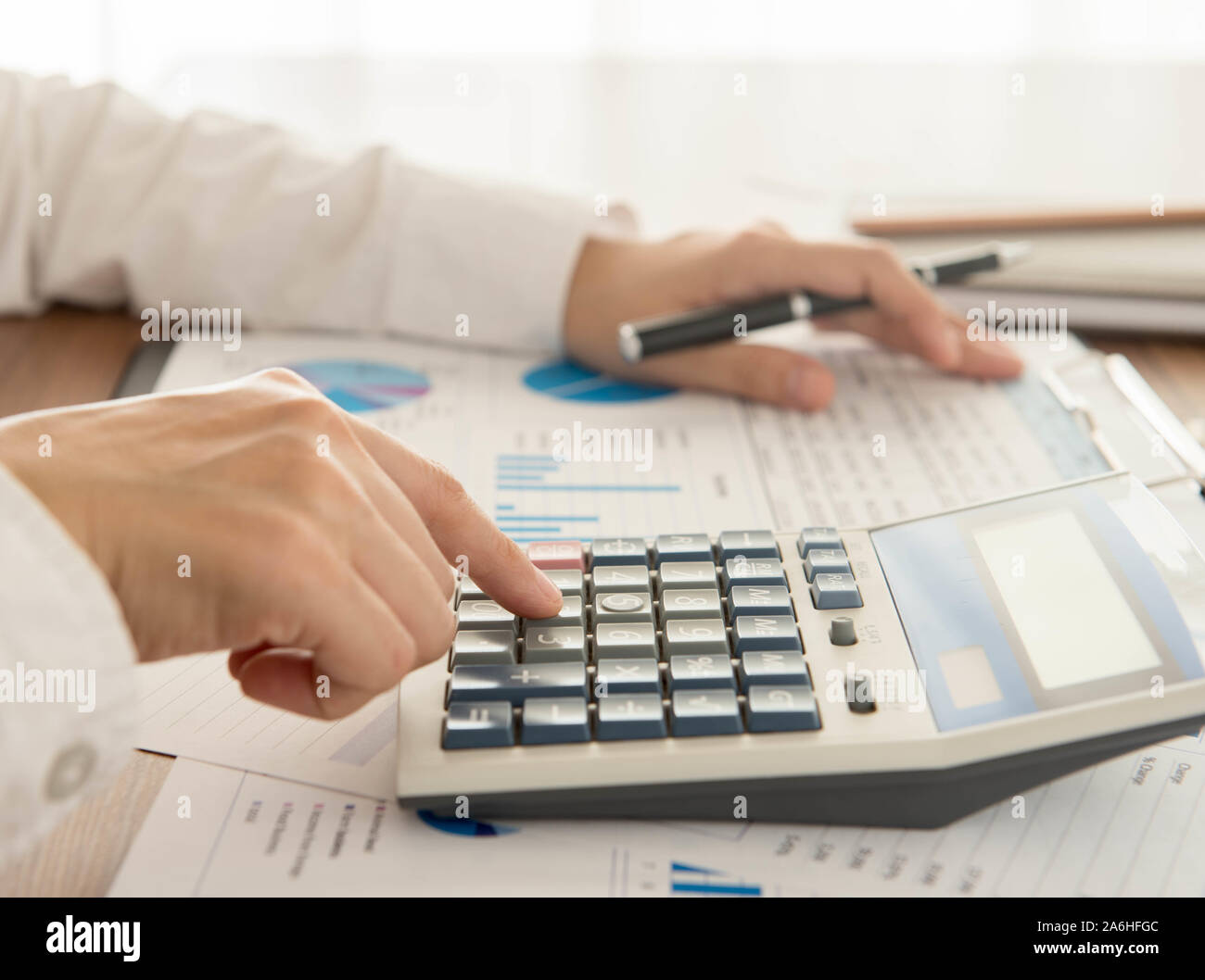 Businessman using a calculator to calculate the numbers Stock Photo - Alamy