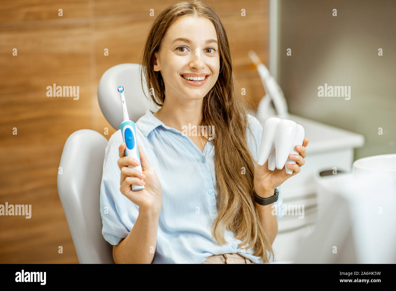 Portrait of a young and cheerful patient with electric toothbrush on ...