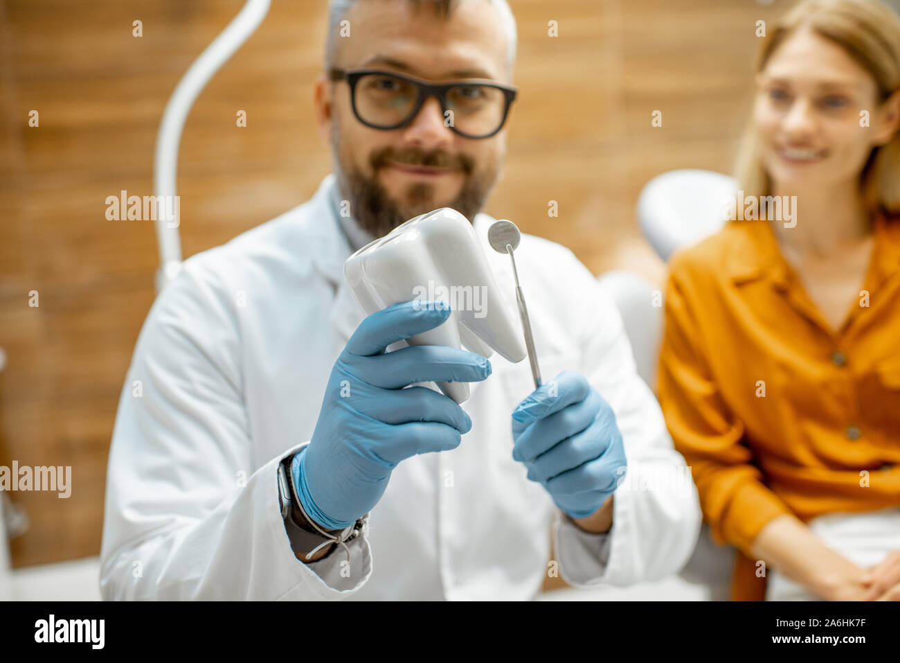 Portrait of a handsome dentist with tooth model and adult patient ...
