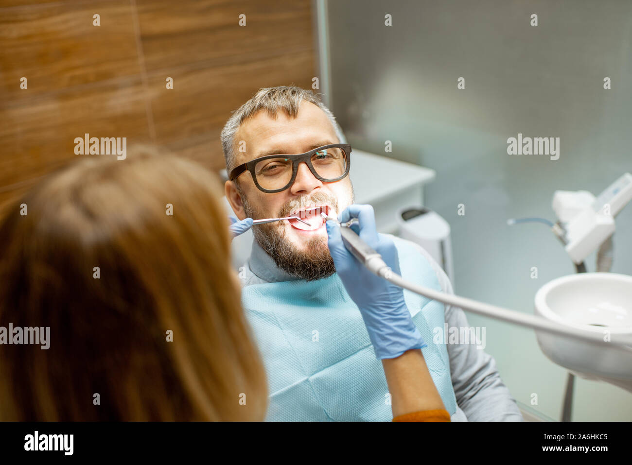 Handsome man as a patient during a teeth inspection with a female ...