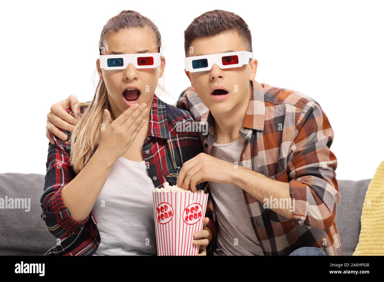 Young male and female watching a 3d movie and eating popcorn isolated on white background Stock ...