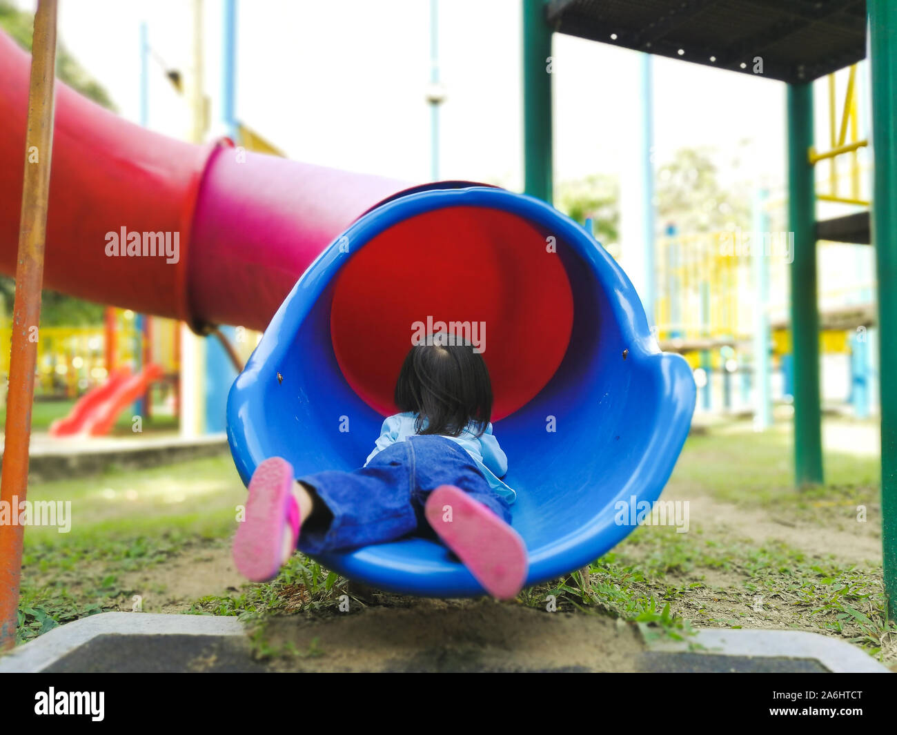 toddler playing on the bottom of a slide at a playground Stock Photo ...