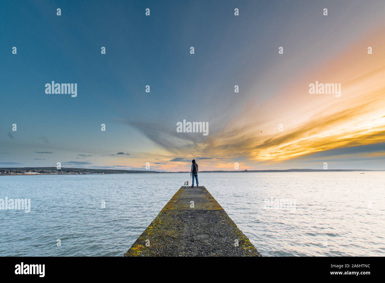 Man standing on pier / breakwater looking out to sea at sunrise Stock ...