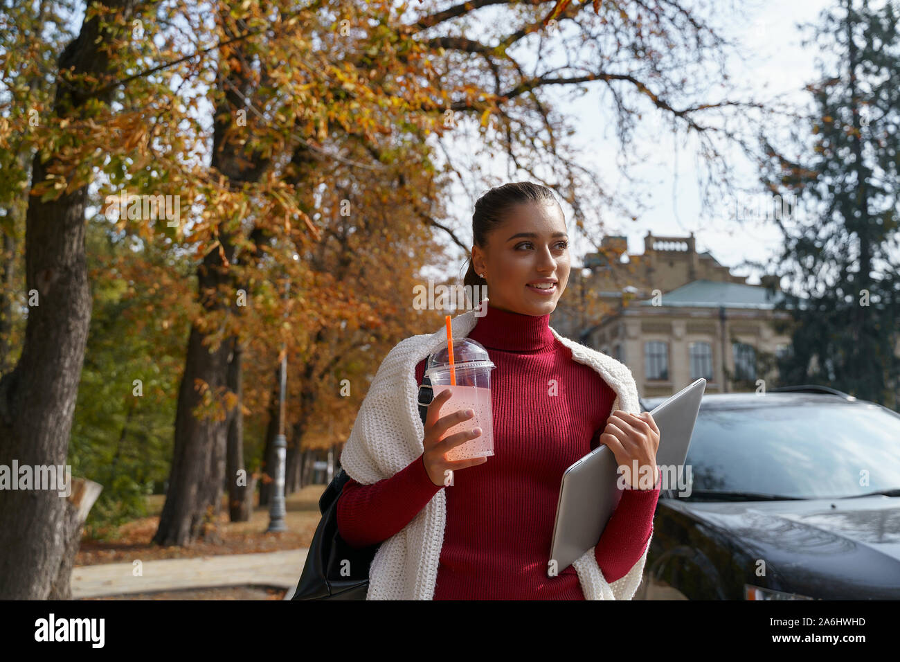 Pretty young woman walking down the street hoding her laptop Stock ...
