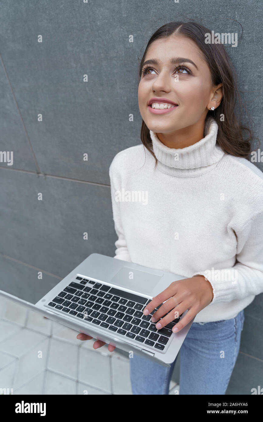 Cheerful and beautiful young woman looking up and typing Stock Photo ...