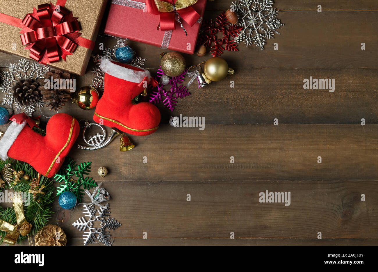 Small santa claus boot with decorations and gift boxes on wooden board ...