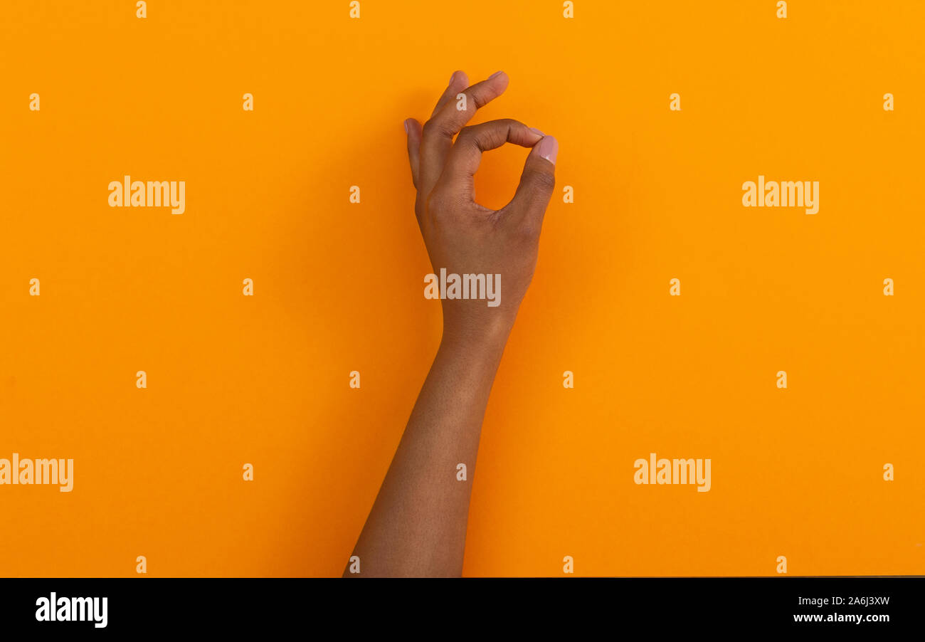 Black female hand showing ok sign over orange background Stock Photo ...