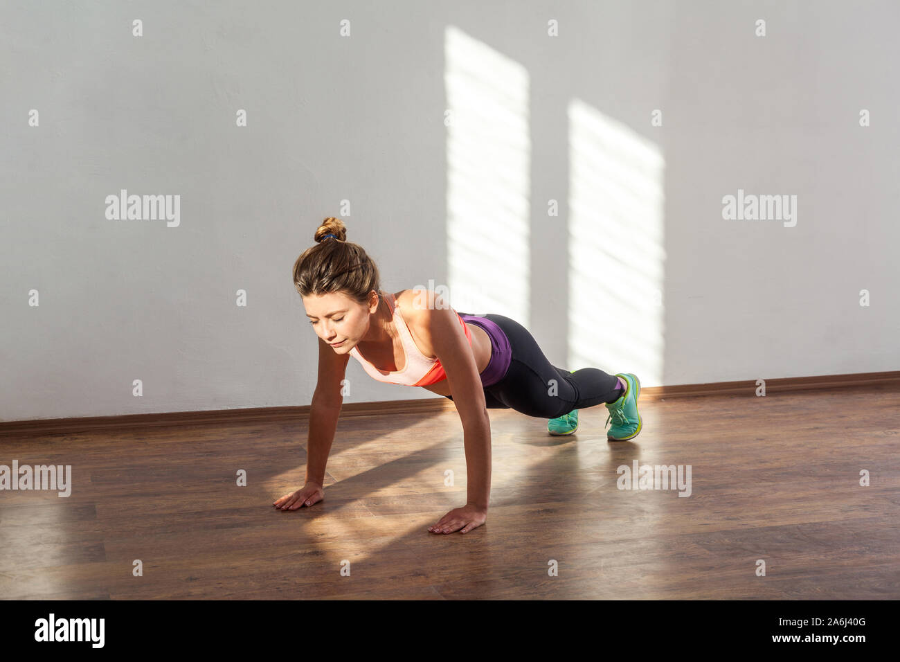 Concentrated athletic beautiful woman with bun hairstyle and in tight ...