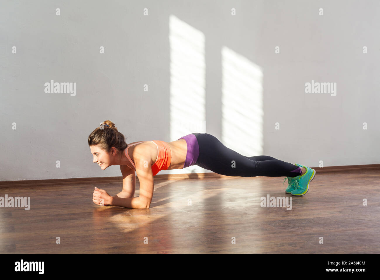 Positive athletic woman with bun hairstyle and in sportswear practicing ...