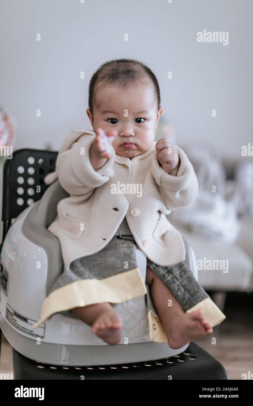 Cute baby boy sitting and raising his hand at home Stock Photo - Alamy