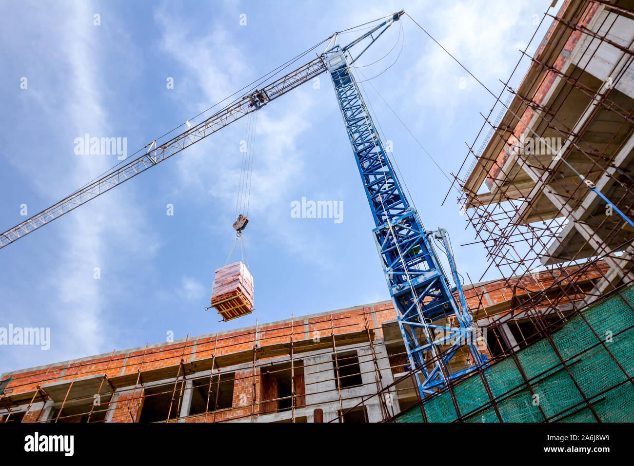 Crane is transport pack of red blocks over building site, raise up for ...