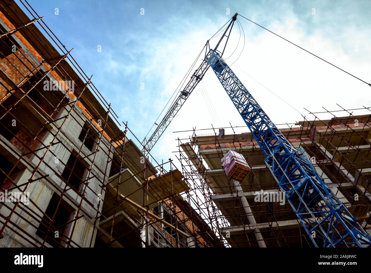 Crane is transport pack of red blocks over building site, raise up for ...