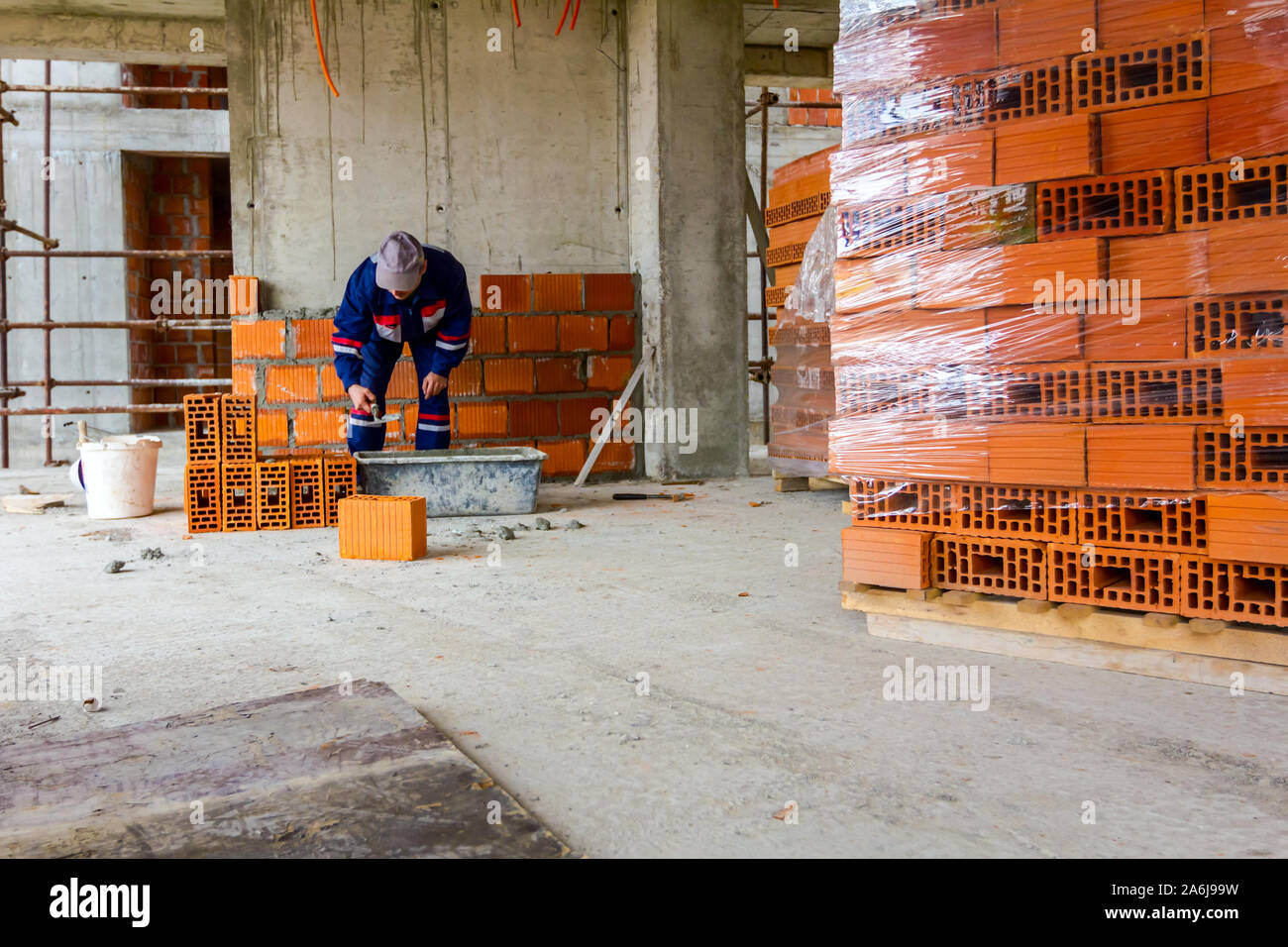 Mason, bricklayer worker is using red blocks to mount a wall at ...