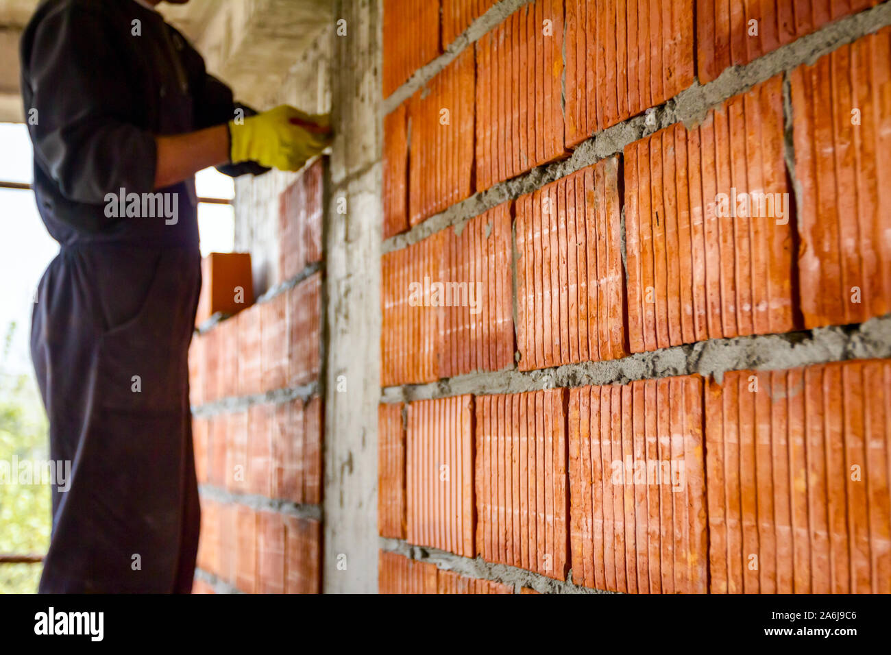 Mason, bricklayer worker is using red blocks to mount a wall at ...