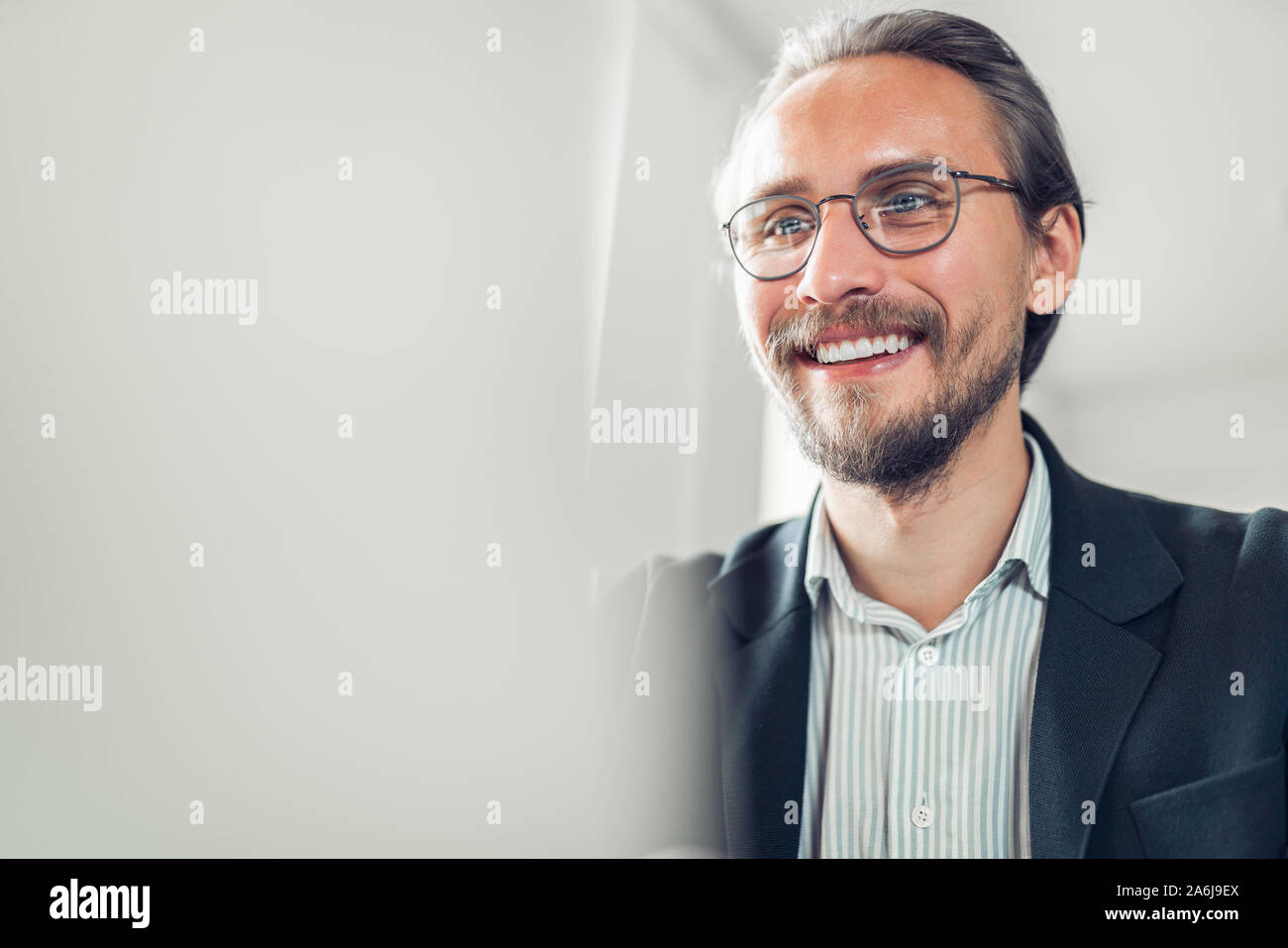 Photo of a Handsome focused and smiling young man sitting by the desk ...
