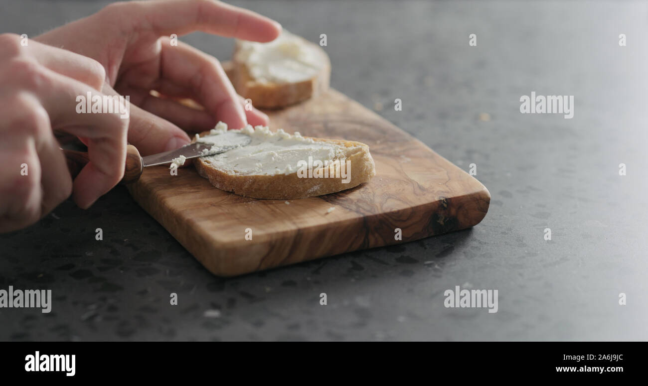 man hand spreading cream cheese on slice of ciabatta, wide photo Stock ...