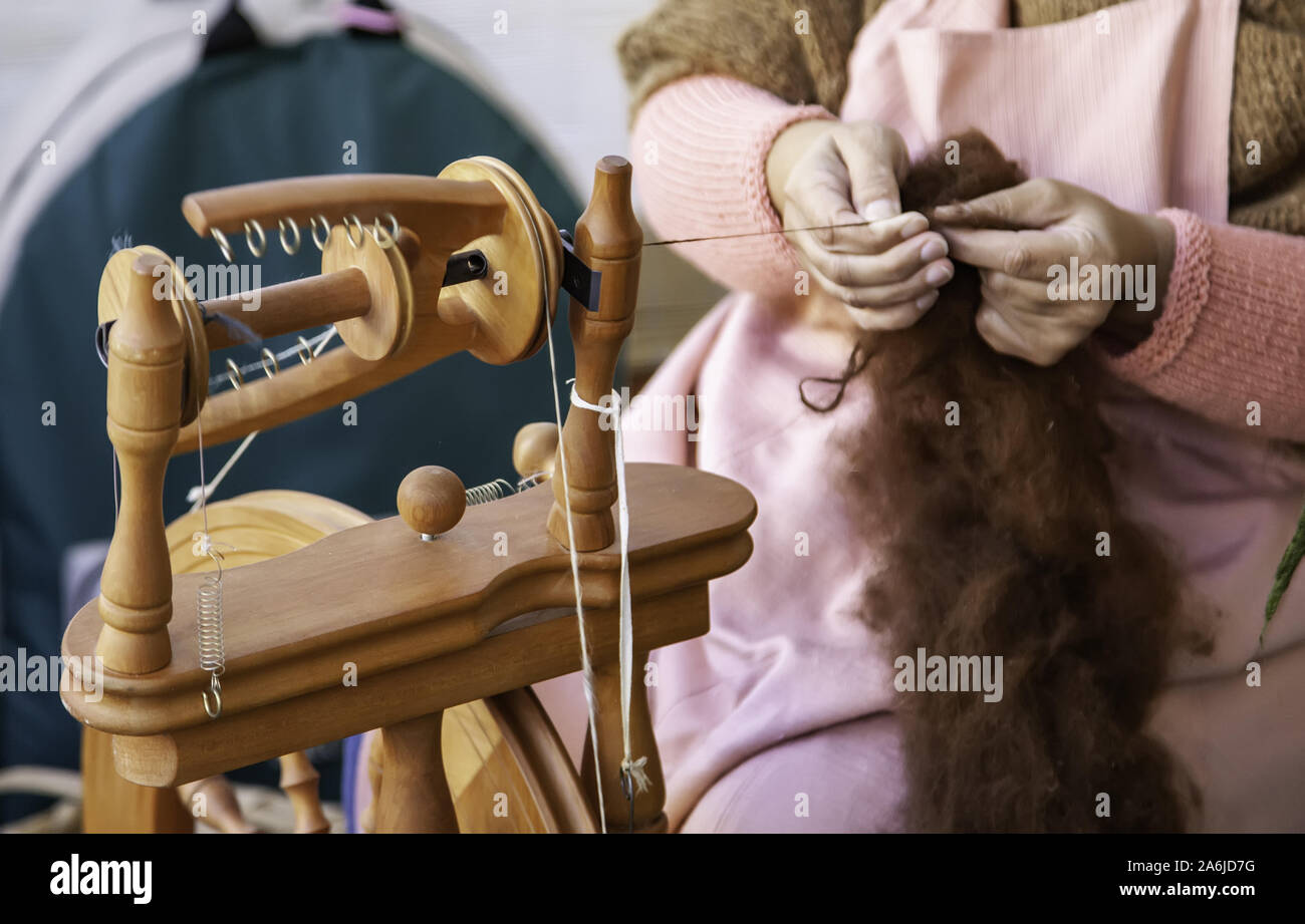 Spinning with a wooden spinning wheel, handicraft detail, thread ...