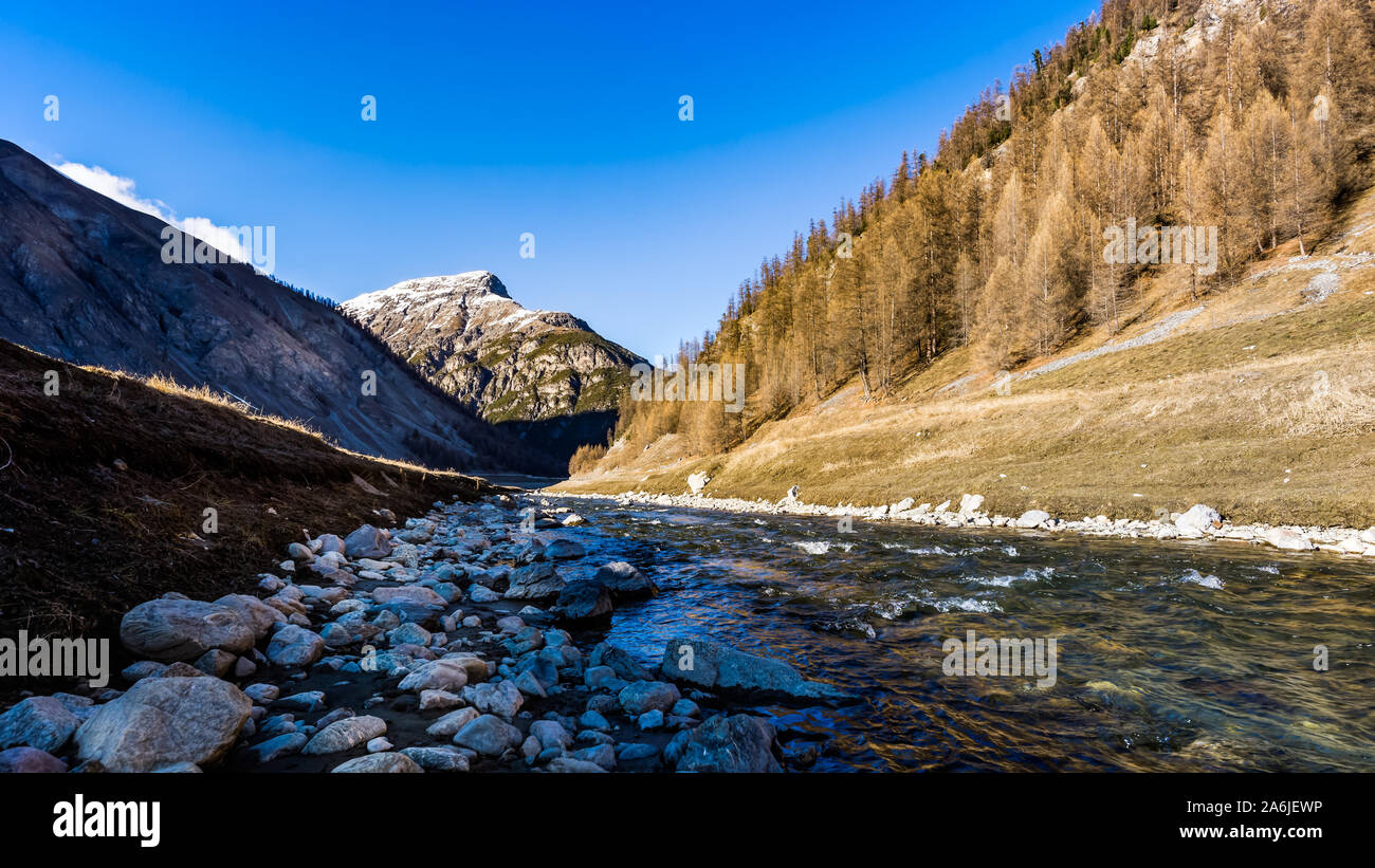 Beautiful mountain valley with stream, trees, puffy clouds and blue sky ...
