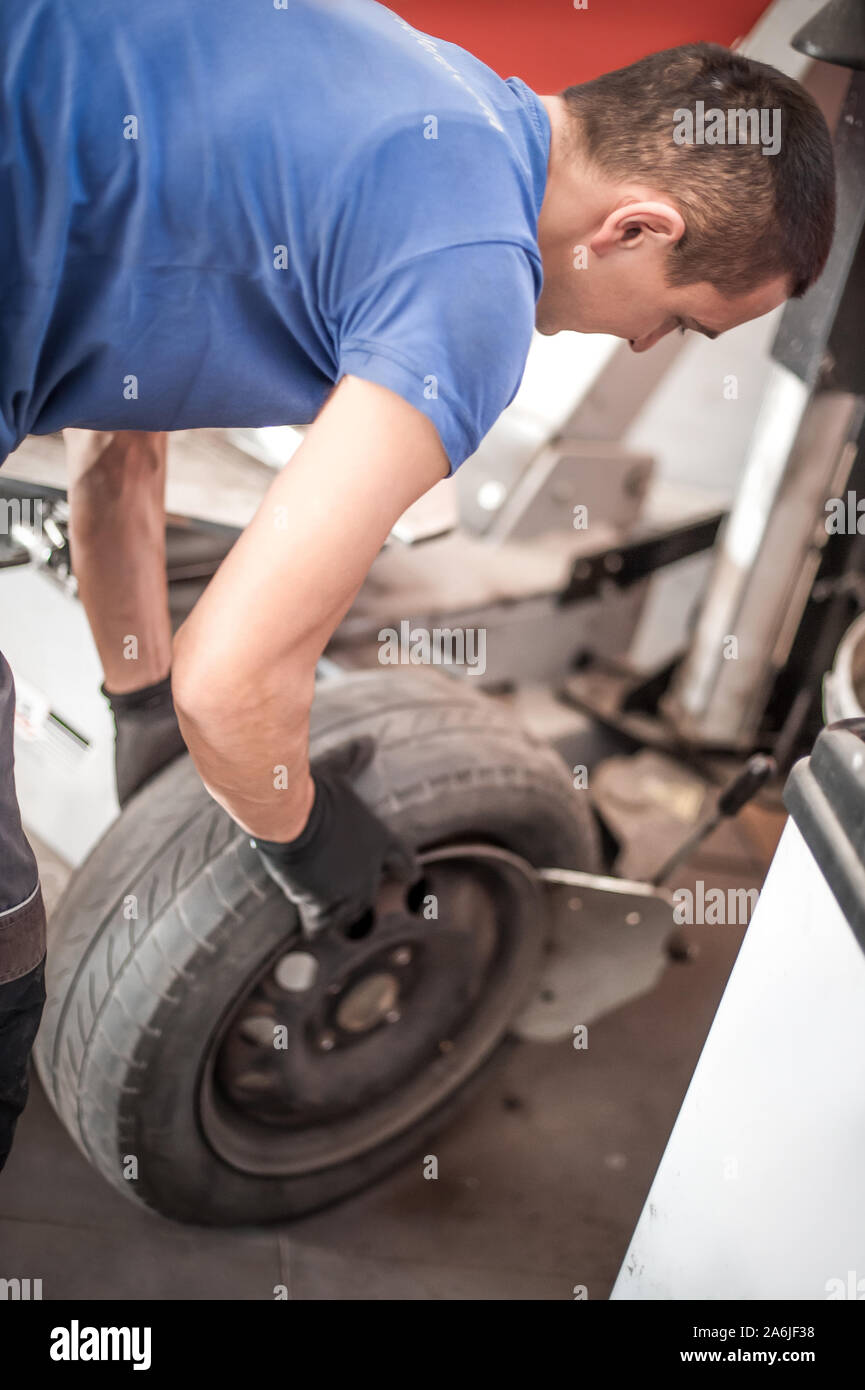 Car master mechanic vulcanizer replaces and changes old with new tires in auto vulcanizing and ...