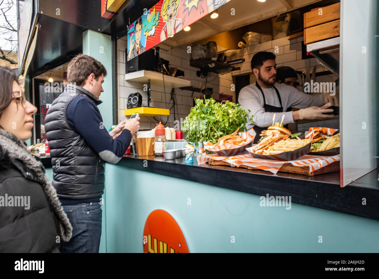 man and woman waiting for food at a Covent Garden food booth Stock ...