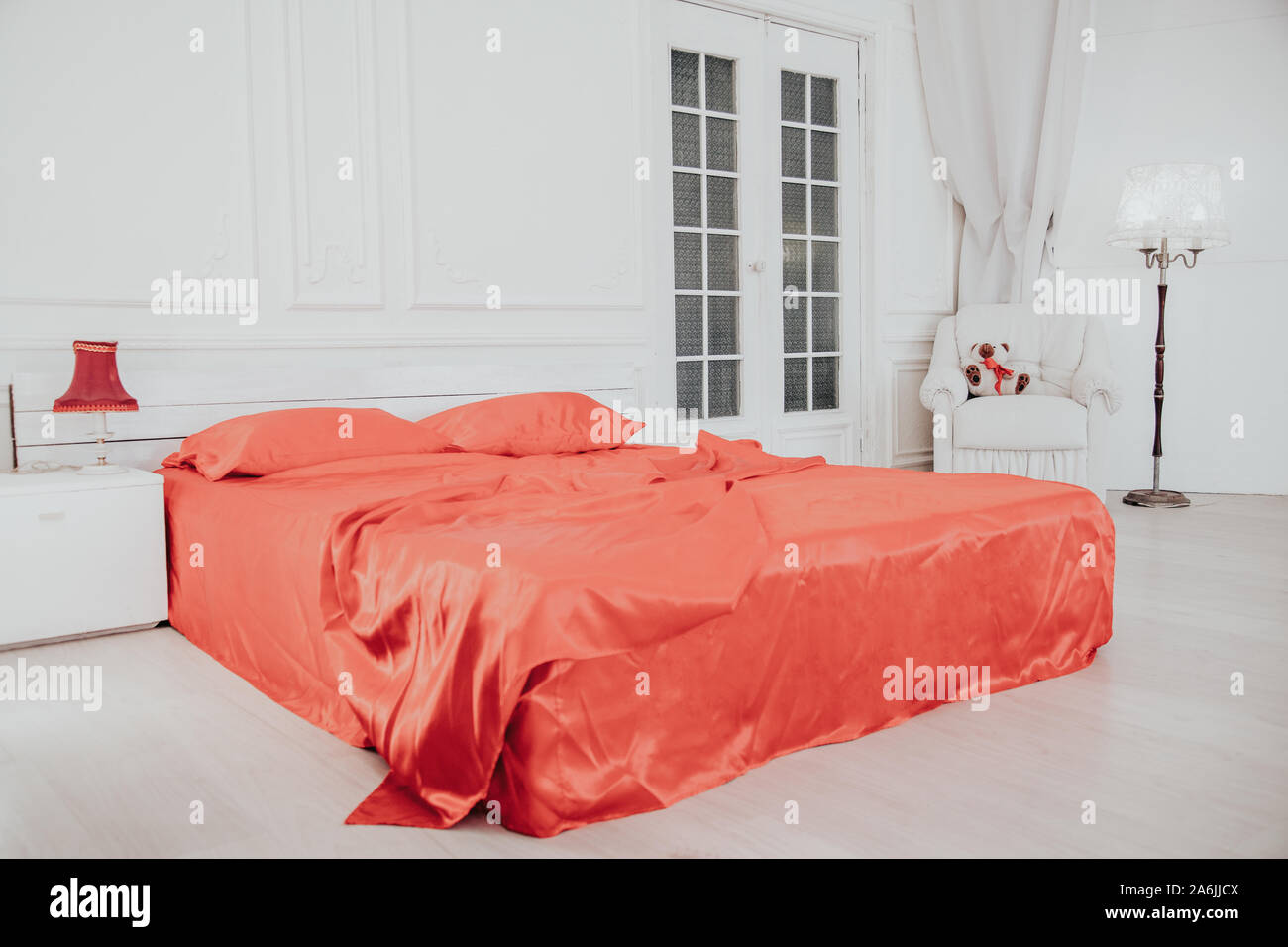 bed with red sheets in white bedroom Interior Stock Photo - Alamy